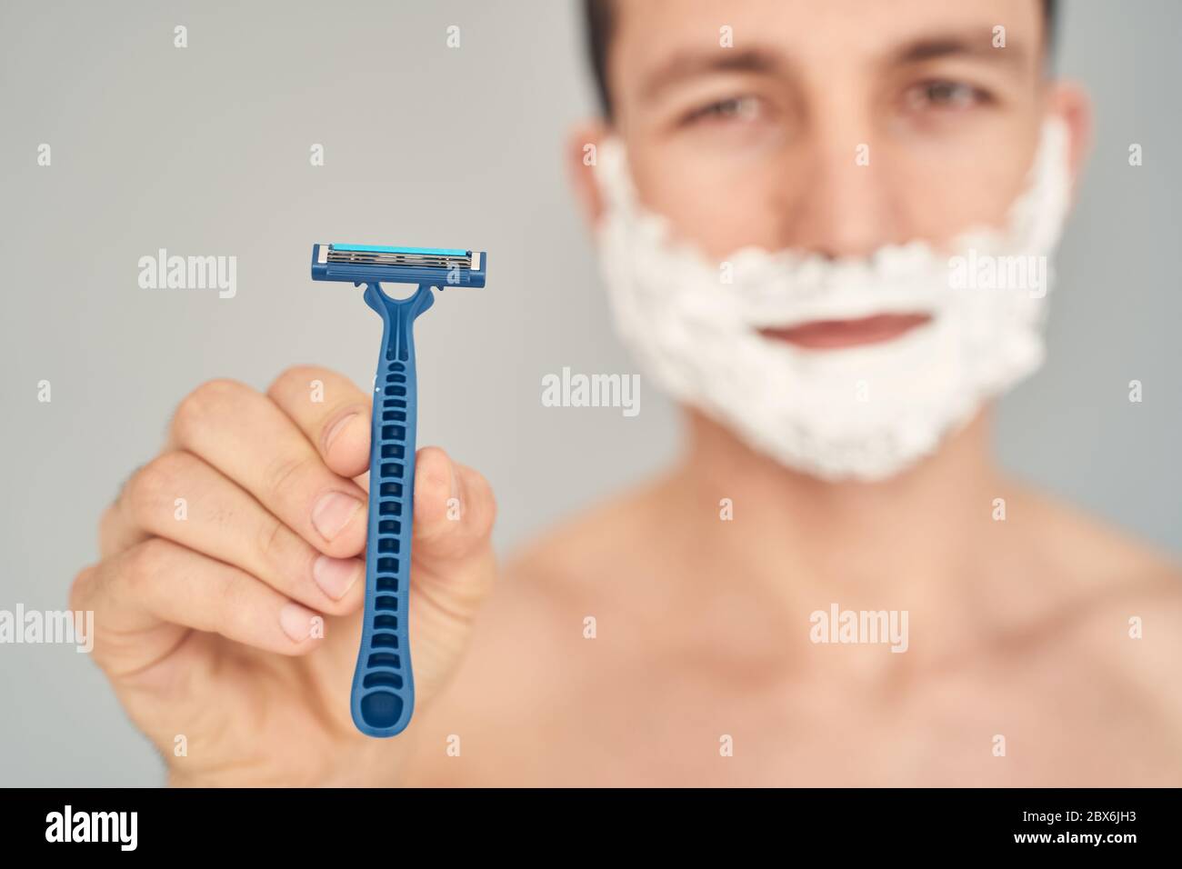 Smiling young man holding razor blade in hand Stock Photo - Alamy