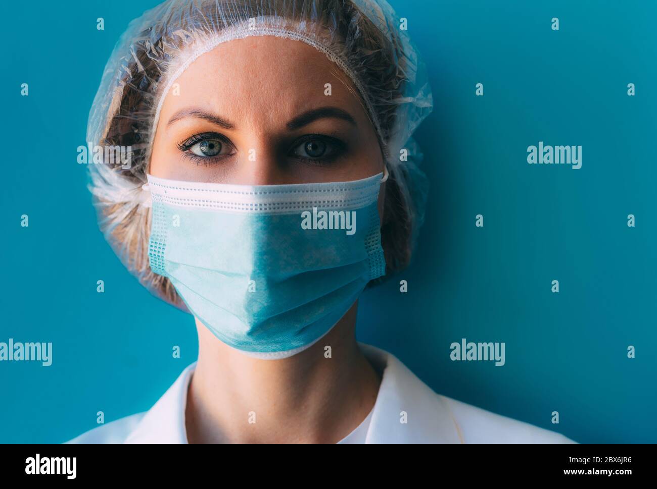 Close-up portrait of young female doctor in medical cap and white gown ...