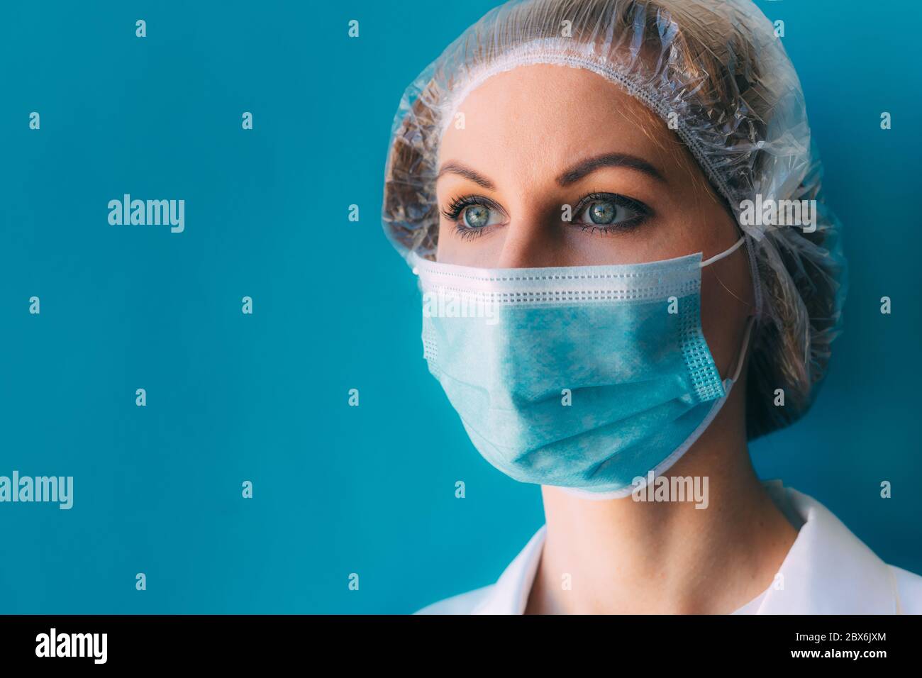 Close-up portrait of young female doctor in medical cap and white gown ...