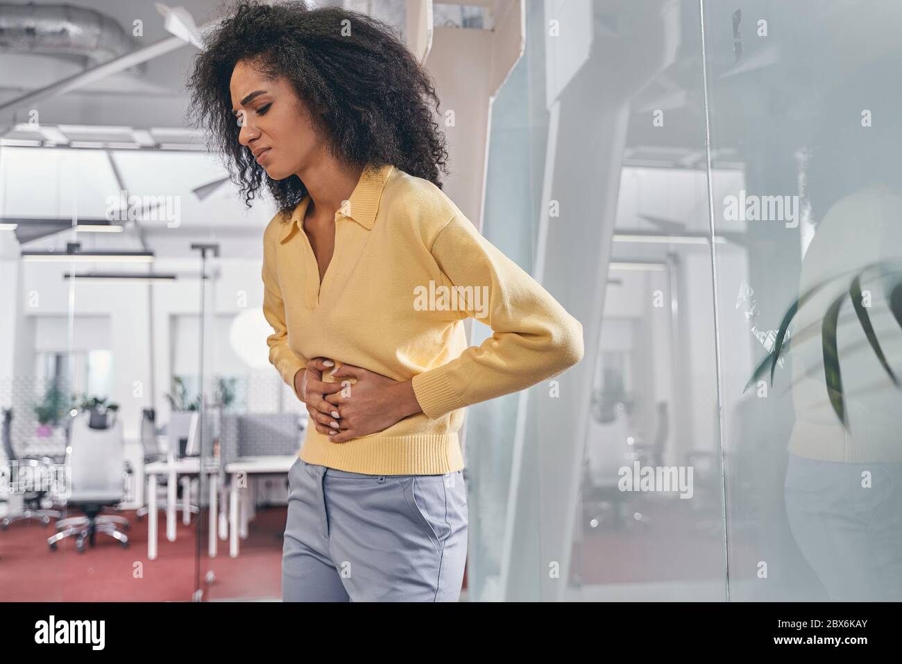 Sad woman suffering from stomach spasms at work Stock Photo - Alamy