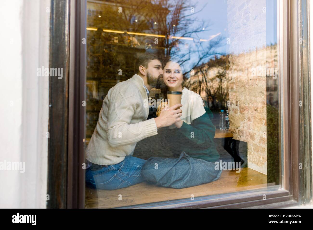 Happy couple eating breakfast sitting near the window in cozy city cafe ...