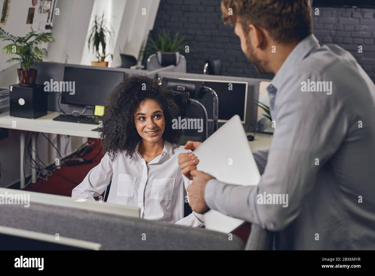 Joyous female employee smiling at her coworker Stock Photo - Alamy