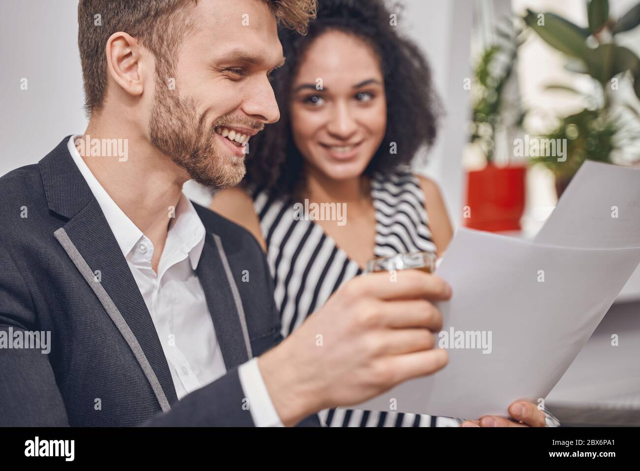 Two smiling young business partners sitting indoors Stock Photo - Alamy