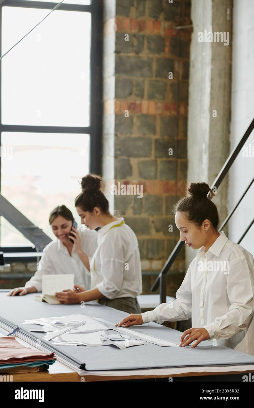 Two young designers of clothes phoning one of clients about order while ...