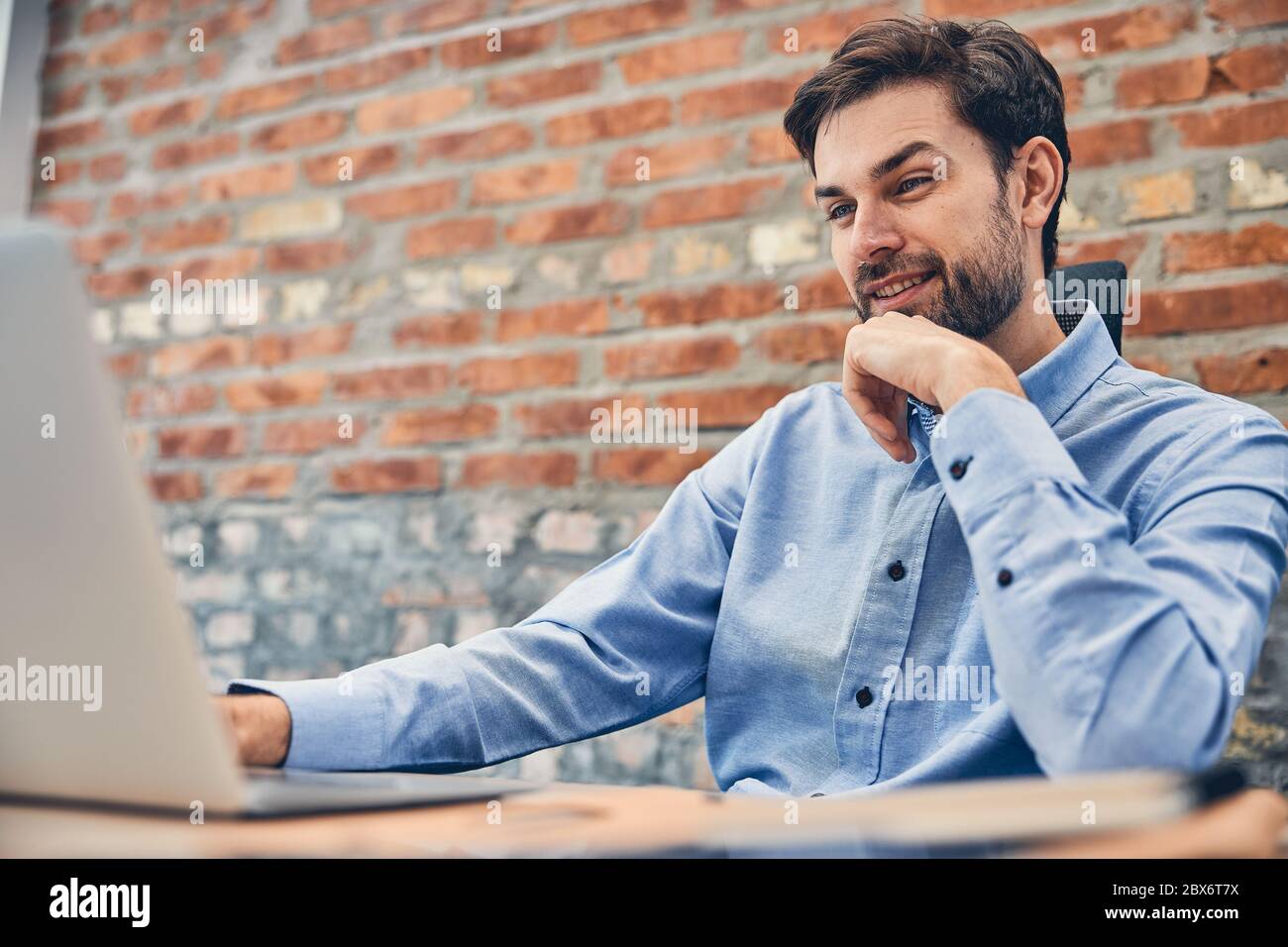 Happy man is using computer at workplace Stock Photo - Alamy