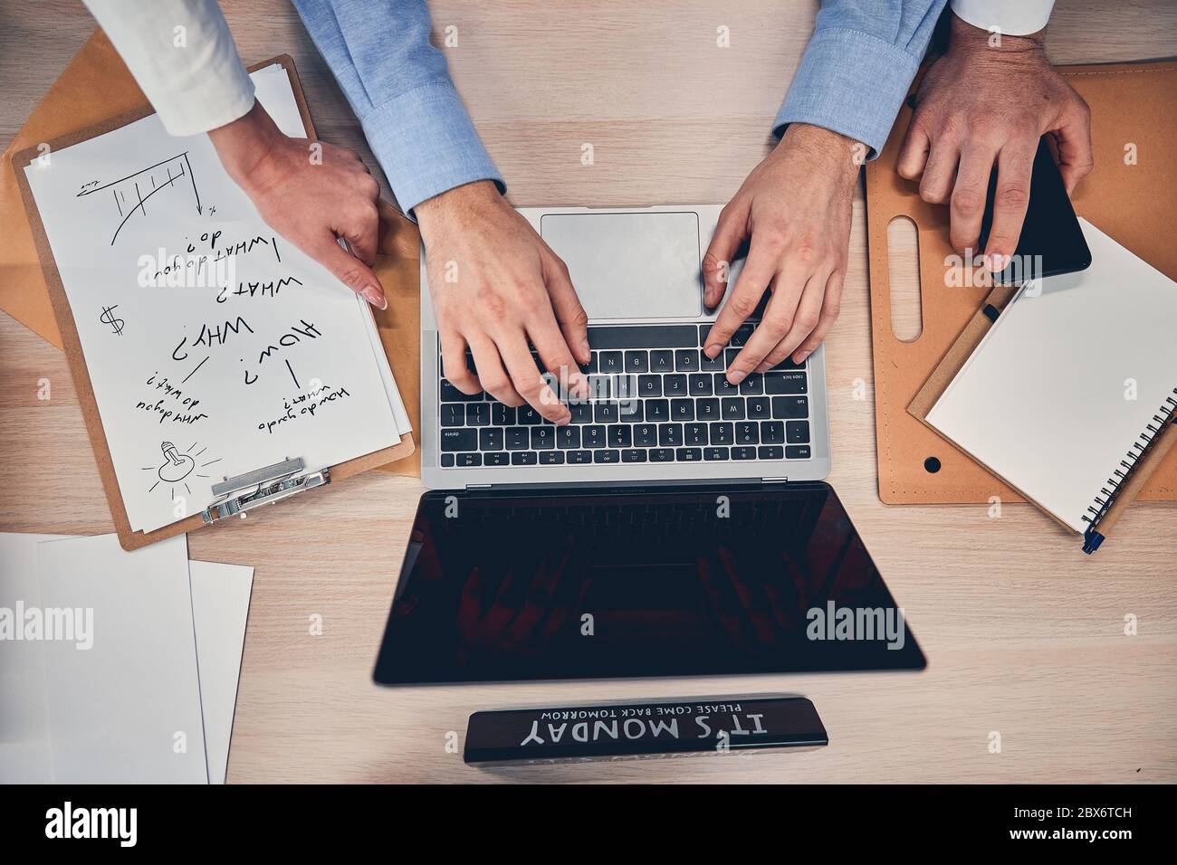 Hands of co-workers typing on laptop, holding smartphone and clipboard ...