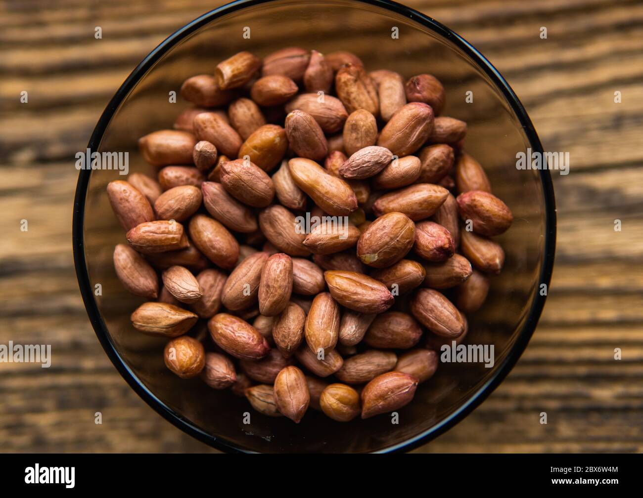 Peanut nuts in a small plate on a vintage wooden table as a background ...