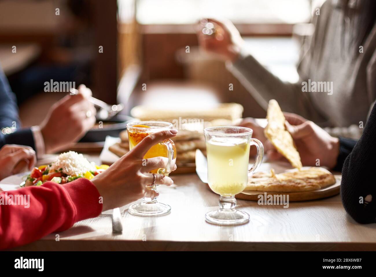 Hands view of young people eating brunch in trendy bar restaurant ...