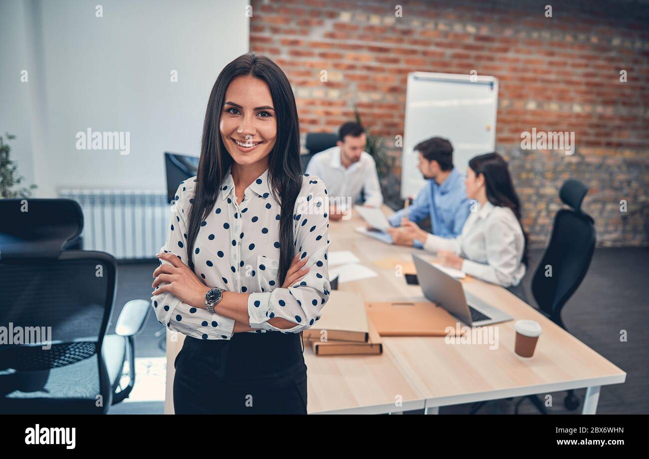 Smiling female manager with folded hands indoors Stock Photo - Alamy