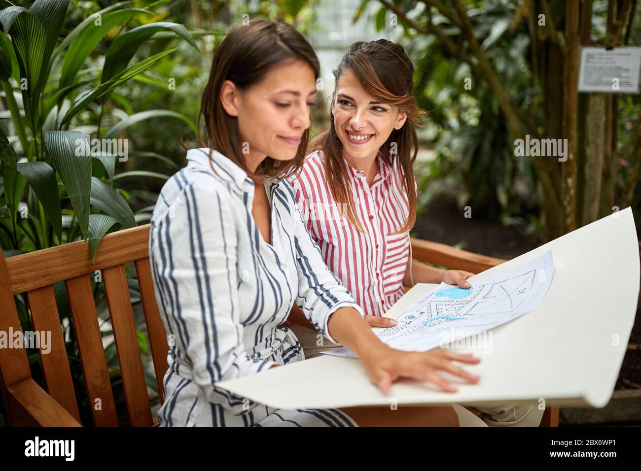 two caucasian female landscape architects sitting on wooden bench in ...