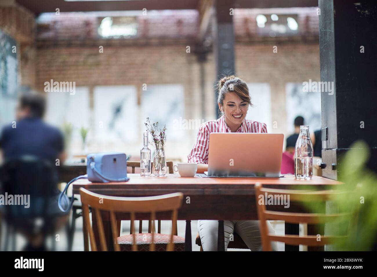young beautiful female watching content on her laptop with headphones ...