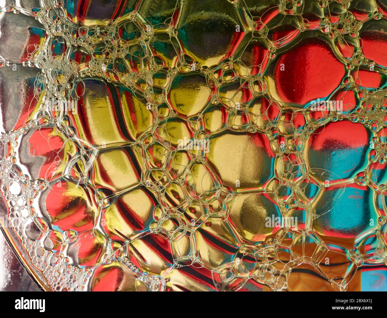 Conceptual close-up still-life of colourful bubbles on a liquid surface ...