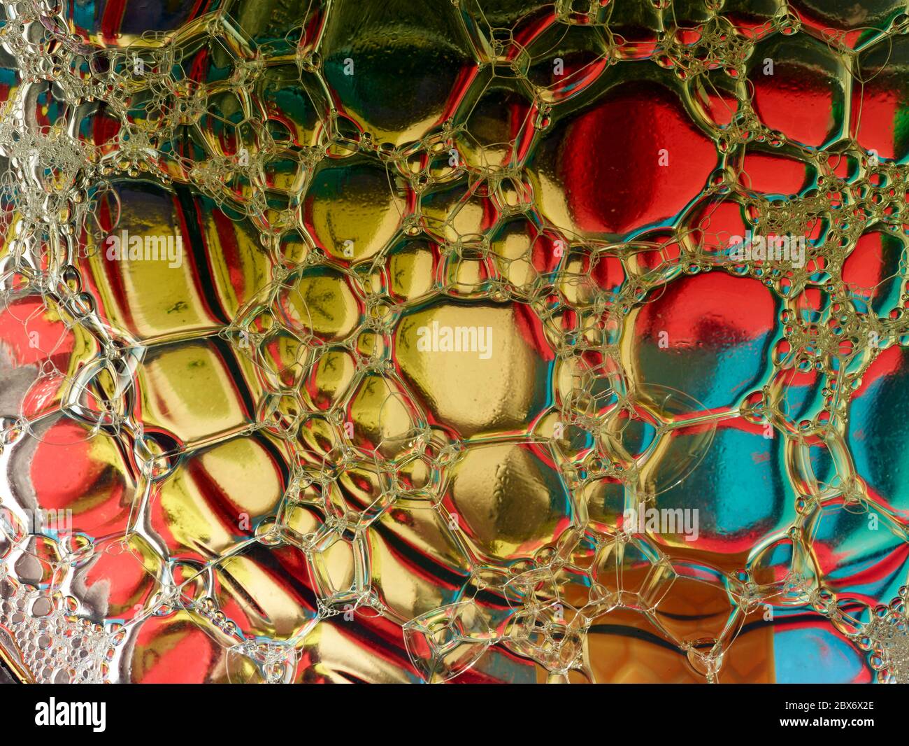 Conceptual close-up still-life of colourful bubbles on a liquid surface ...