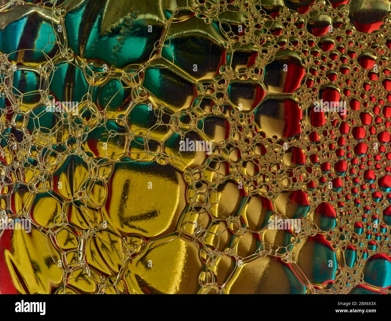 Conceptual close-up still-life of colourful bubbles on a liquid surface ...