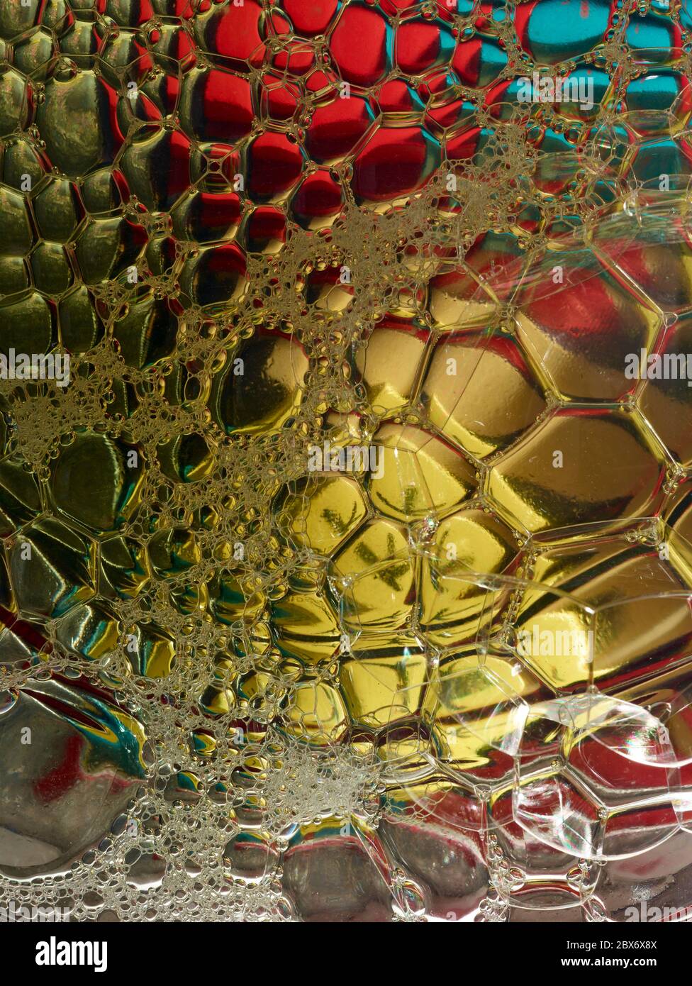 Conceptual close-up still-life of colourful bubbles on a liquid surface ...