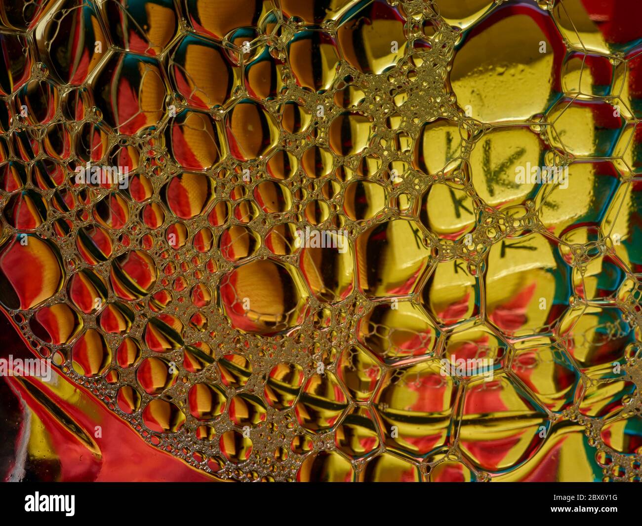 Conceptual close-up still-life of colourful bubbles on a liquid surface ...