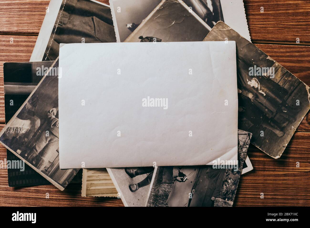 Stack old photos on table. Mock-up blank paper. Postcard rumpled and ...