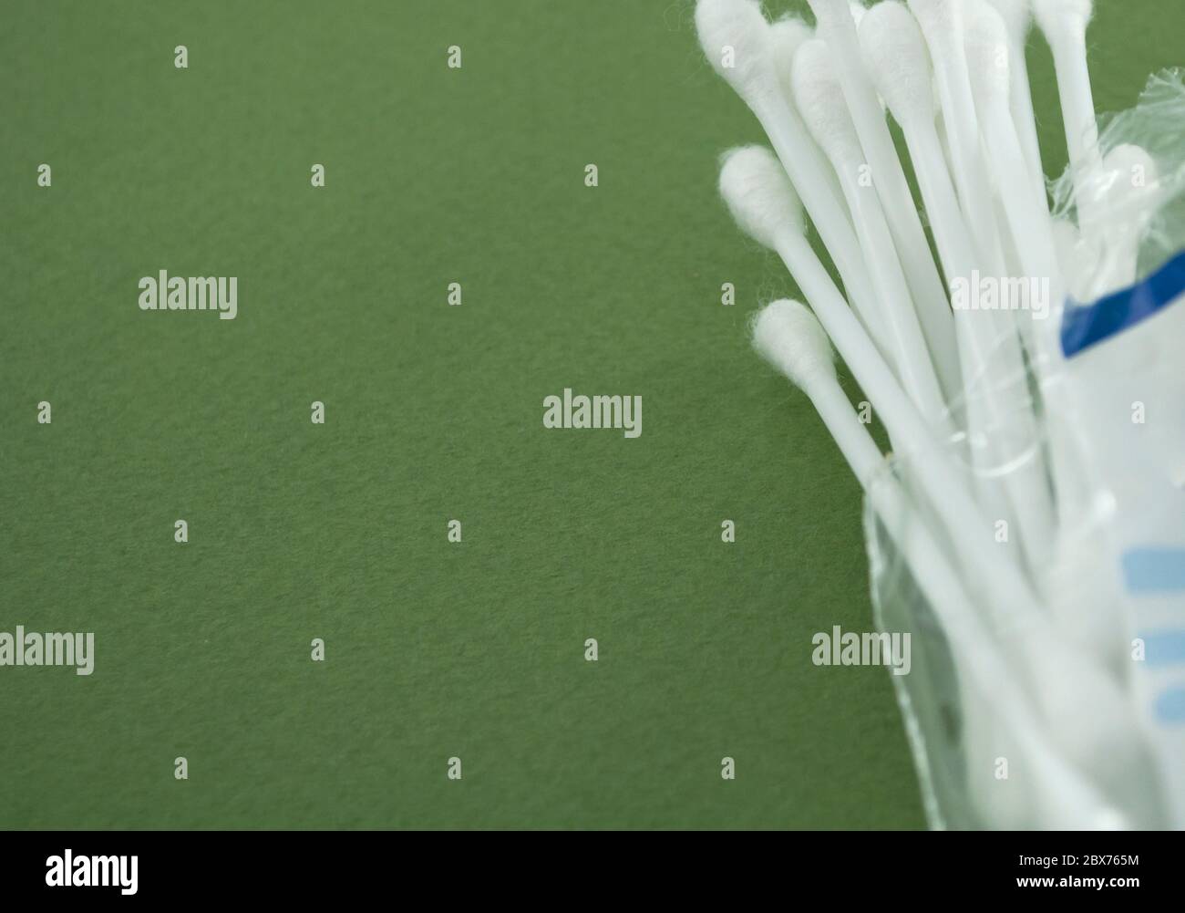 Plastic cotton ear sticks in the started transparent pack on a green ...