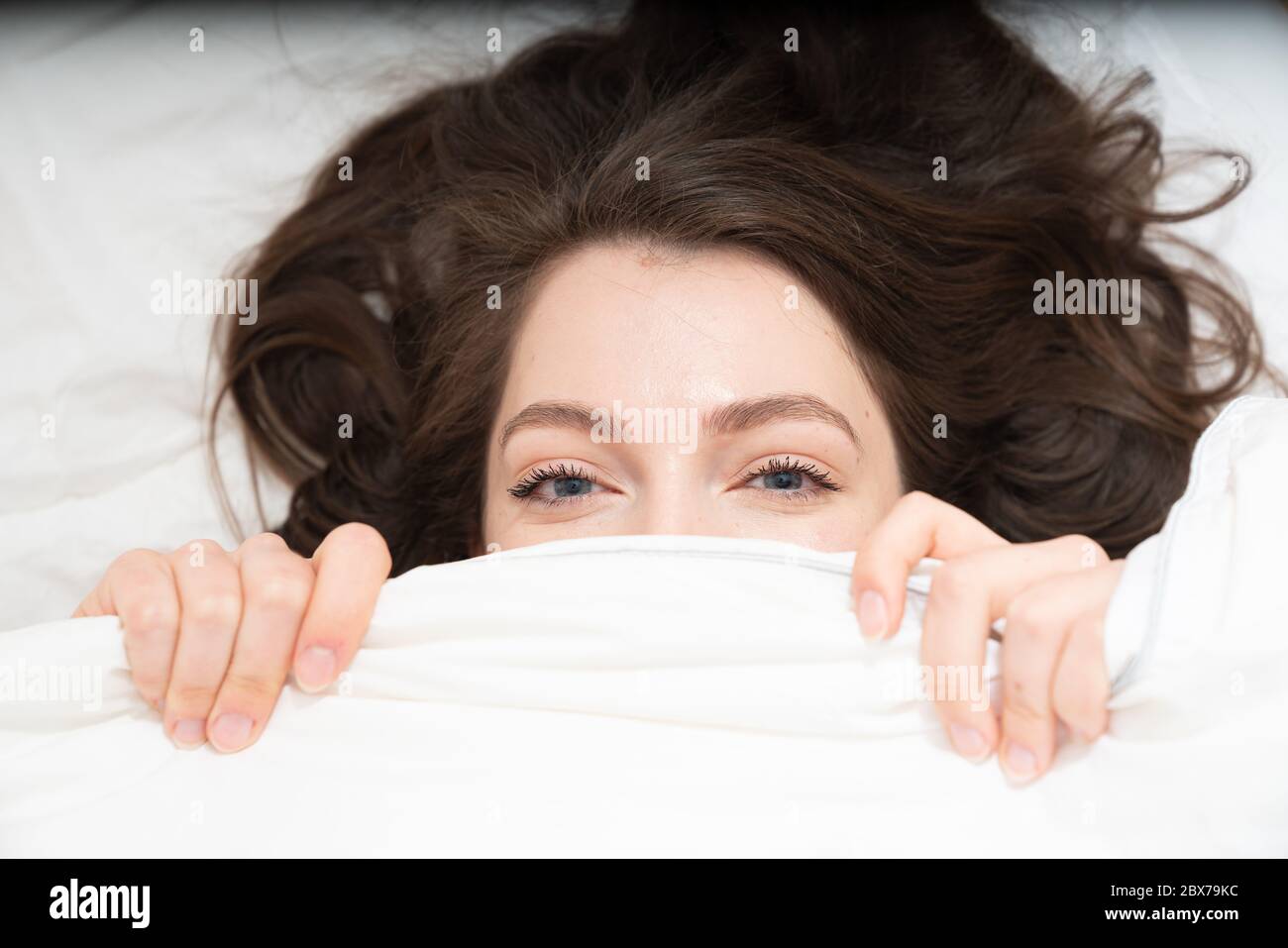 Closeup Of Cute Lovely Young Woman With Long Hair Lying And Hiding