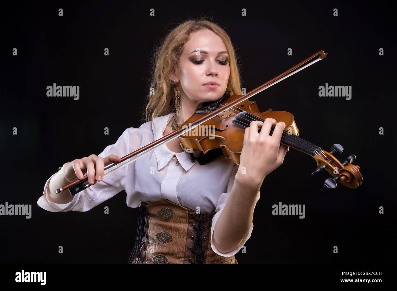 Young blond woman playing the fiddle on black background Stock Photo ...