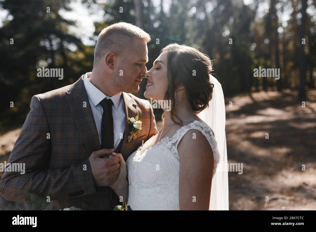 Groom who is going to kiss her smiling bride in the forest. Moment ...
