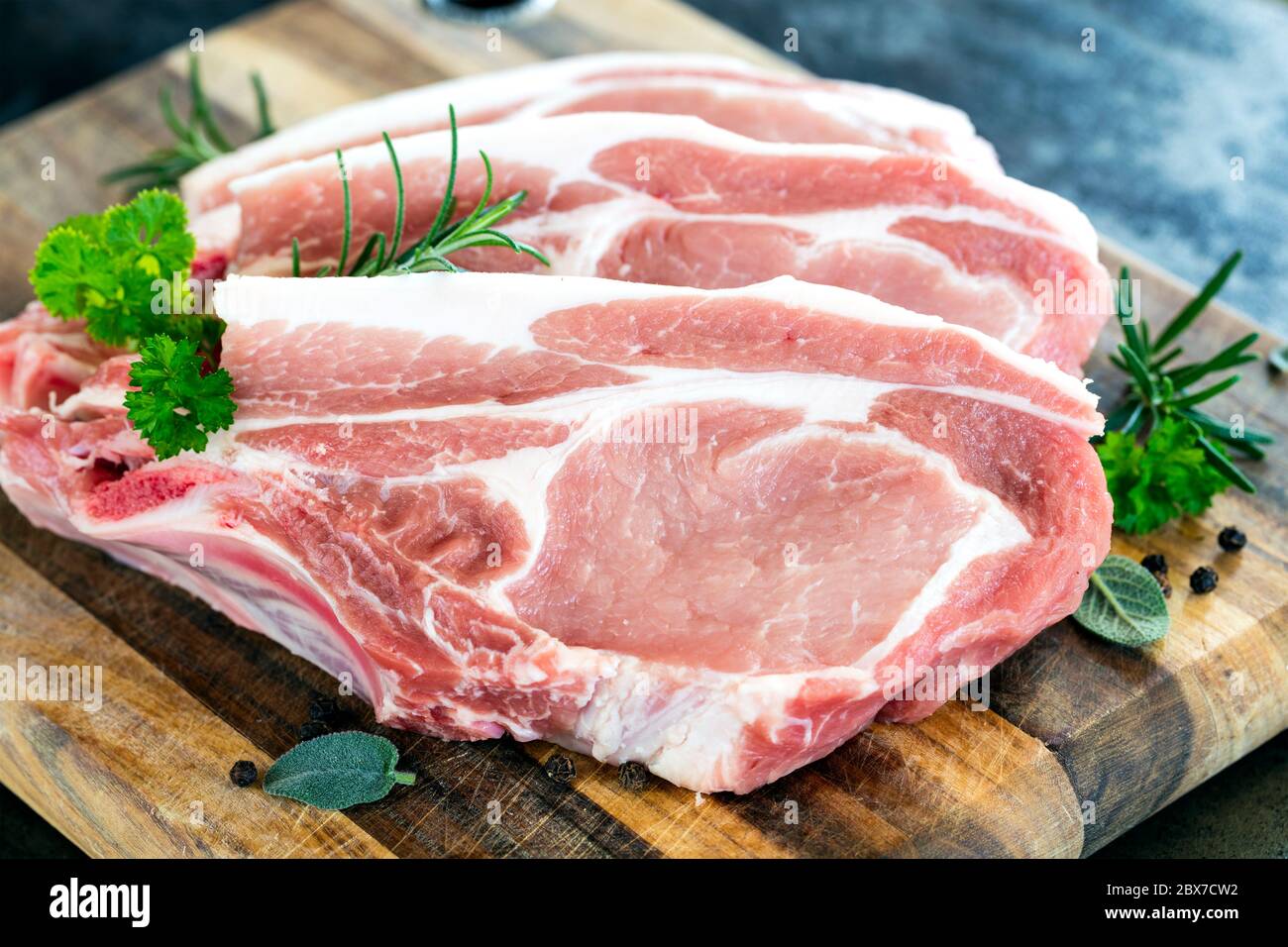 Raw pork chops on chopping board, with fresh herbs and spices Stock ...