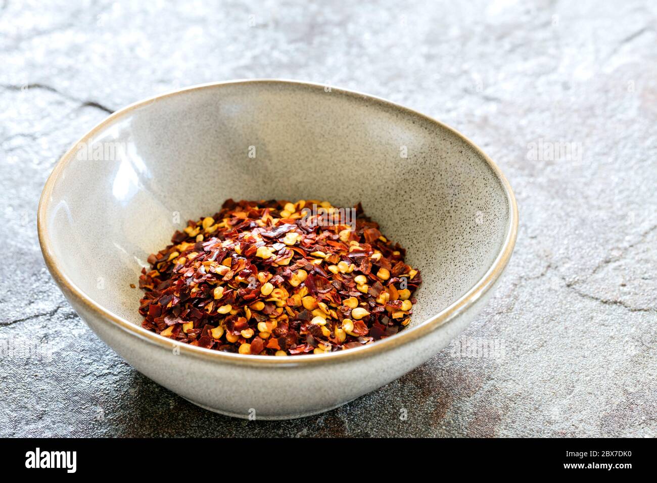 Hot chilli flakes in stoneware bowl over slate background Stock Photo ...