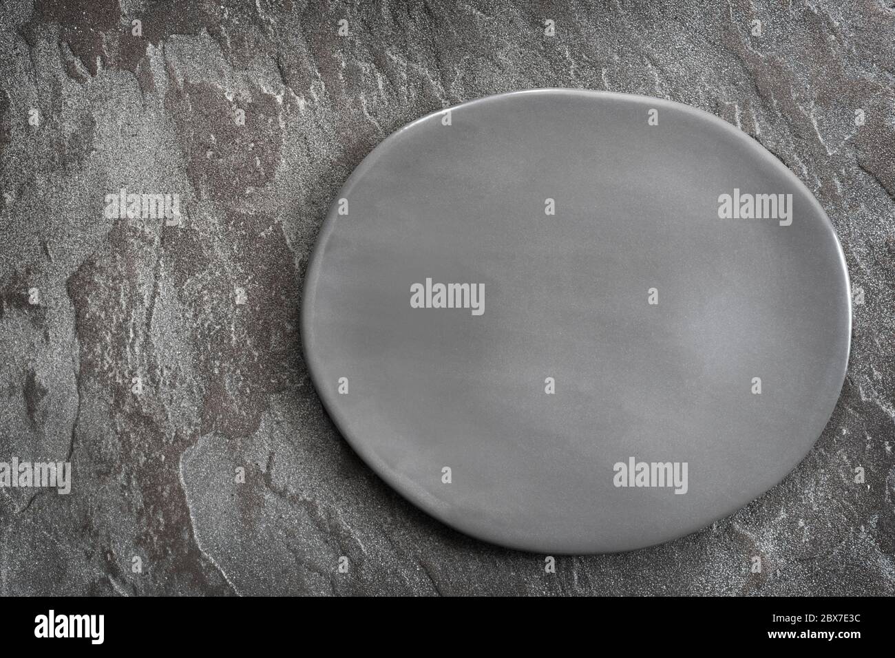 Empty rustic gray oval plate over slate, top view Stock Photo - Alamy