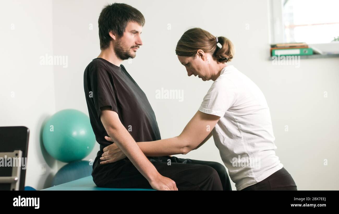 Physiotherapist exercising with disabled person on a therapy table ...