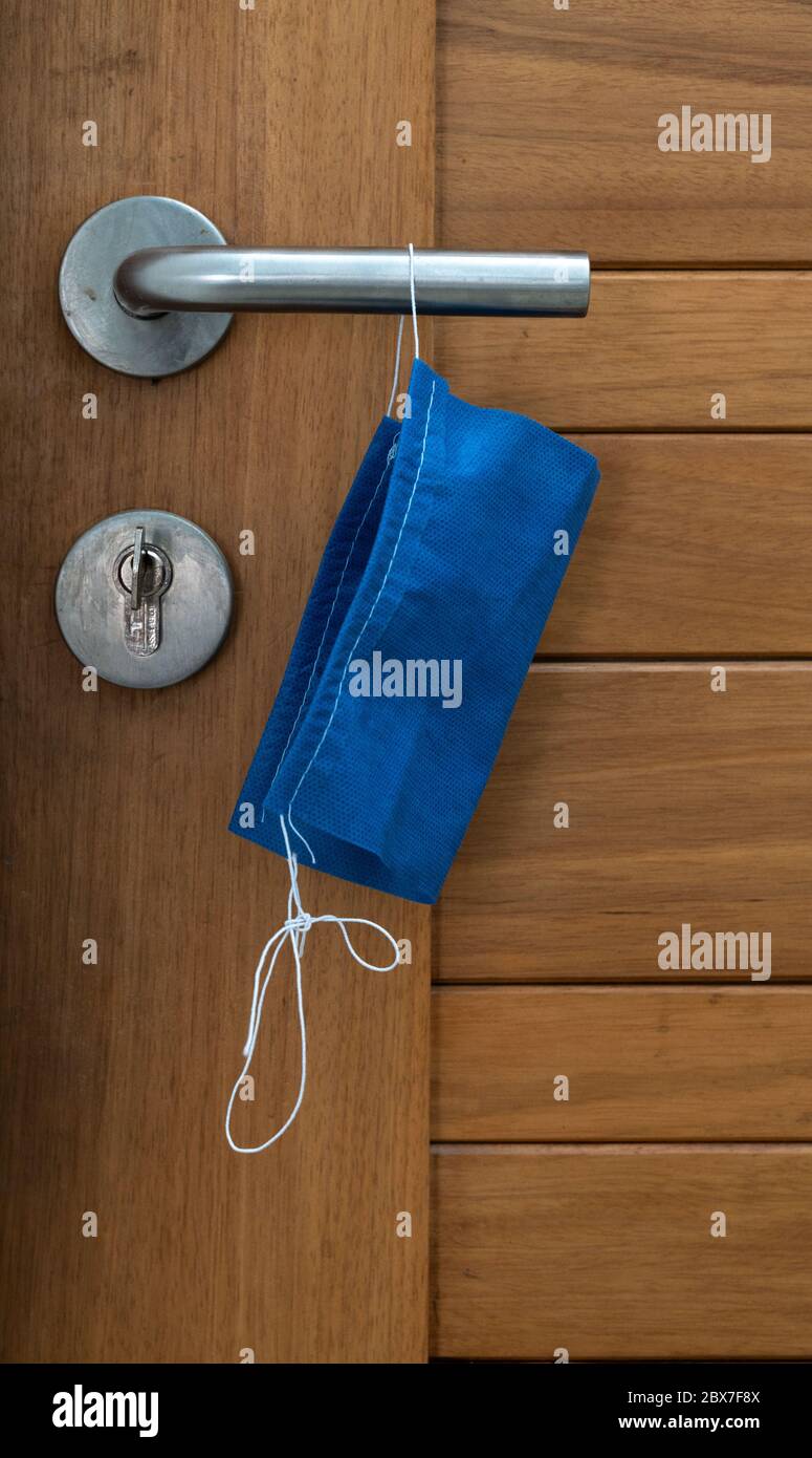Face mask hanging on door handle ready to be worn before going out of ...