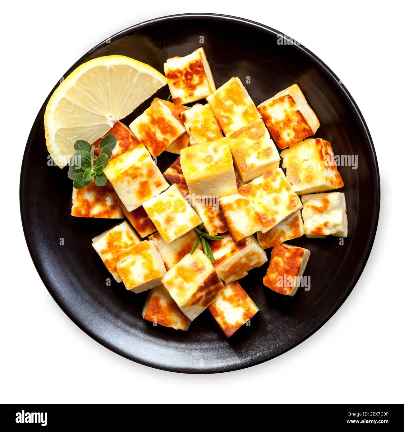 Grilled halloumi cheese cubes with lemon and herbs. On black plate, top ...