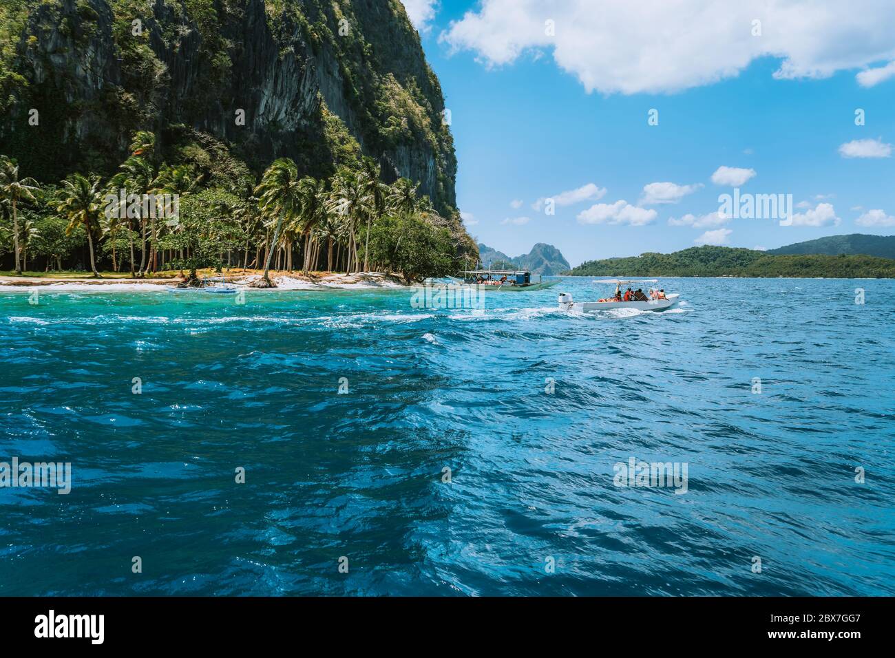 Boat with tourists on ipil beach of exotic island on hopping tour ...