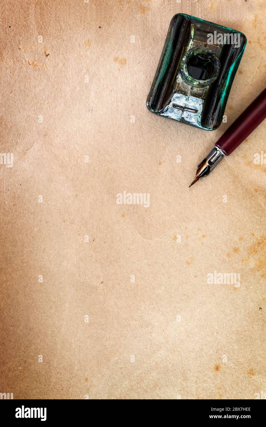 Vintage nib pen and inkwell over old stained paper with copyspace. Top ...
