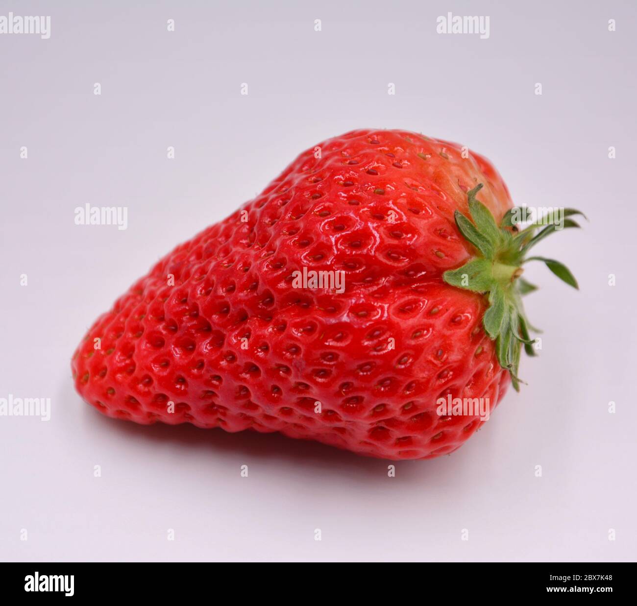One fresh strawberry with little sink on surface with white background ...