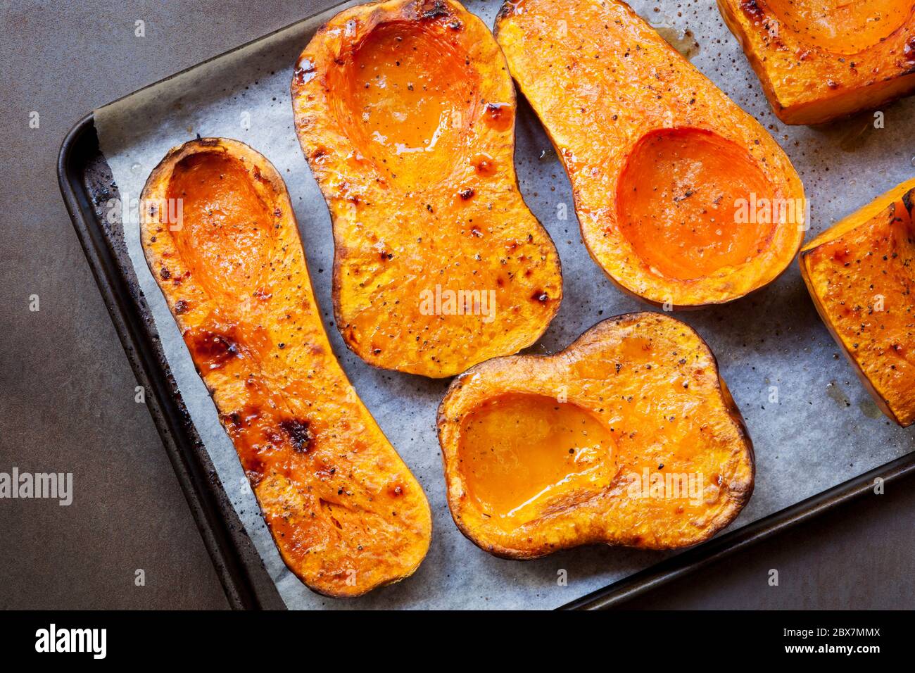 Roasting butternut pumpkin, for a warming soup. Top view on oven tray ...