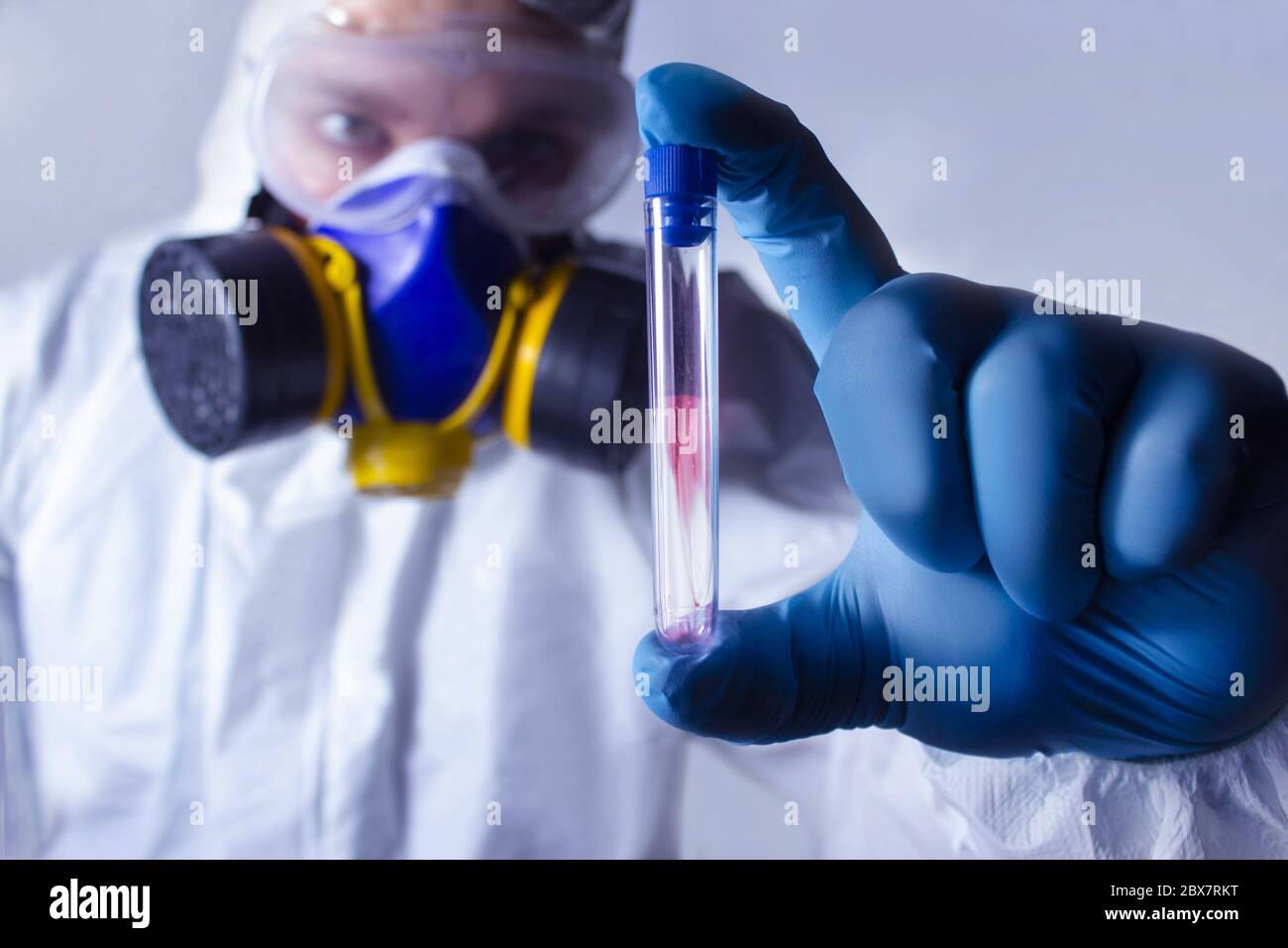 Fully equipped lab worker in respirator, glasses, outfit and blue ...