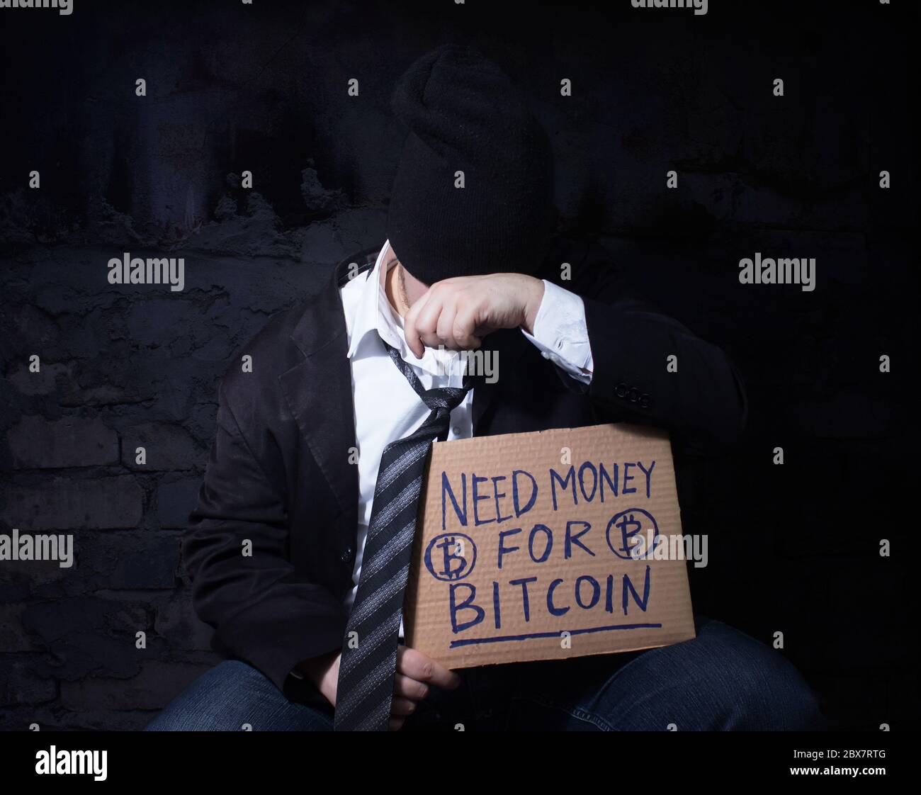 Photo of a depressed homeless businessman with a cardboard bitcoin sign ...