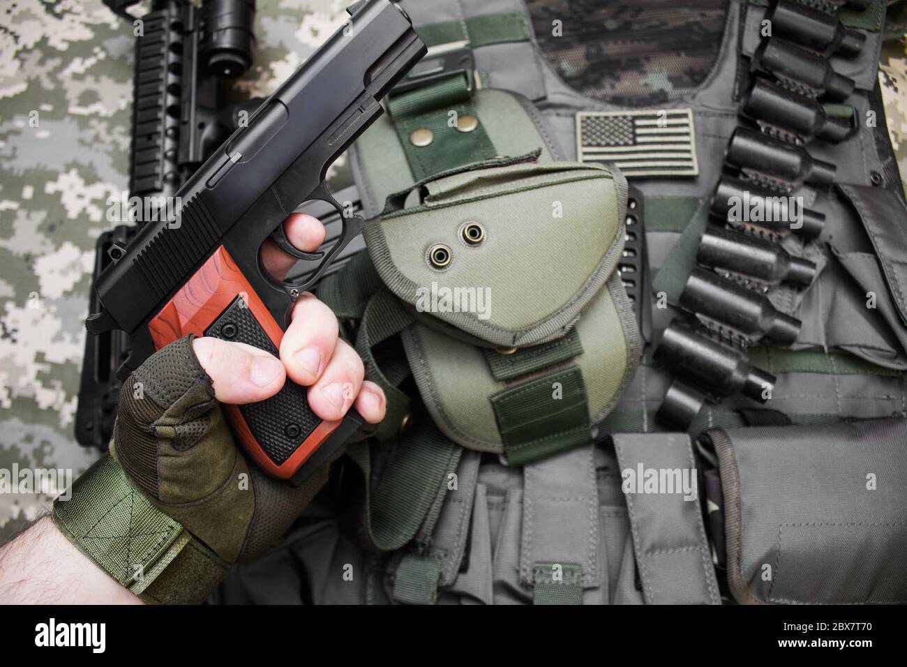 First person view hand in tactical gloves holding a gun on camouflage ...