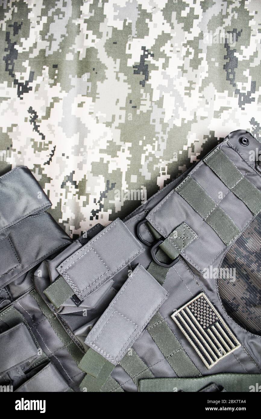 Upper view photo of a military bulletproof vest laying on a camouflage ...