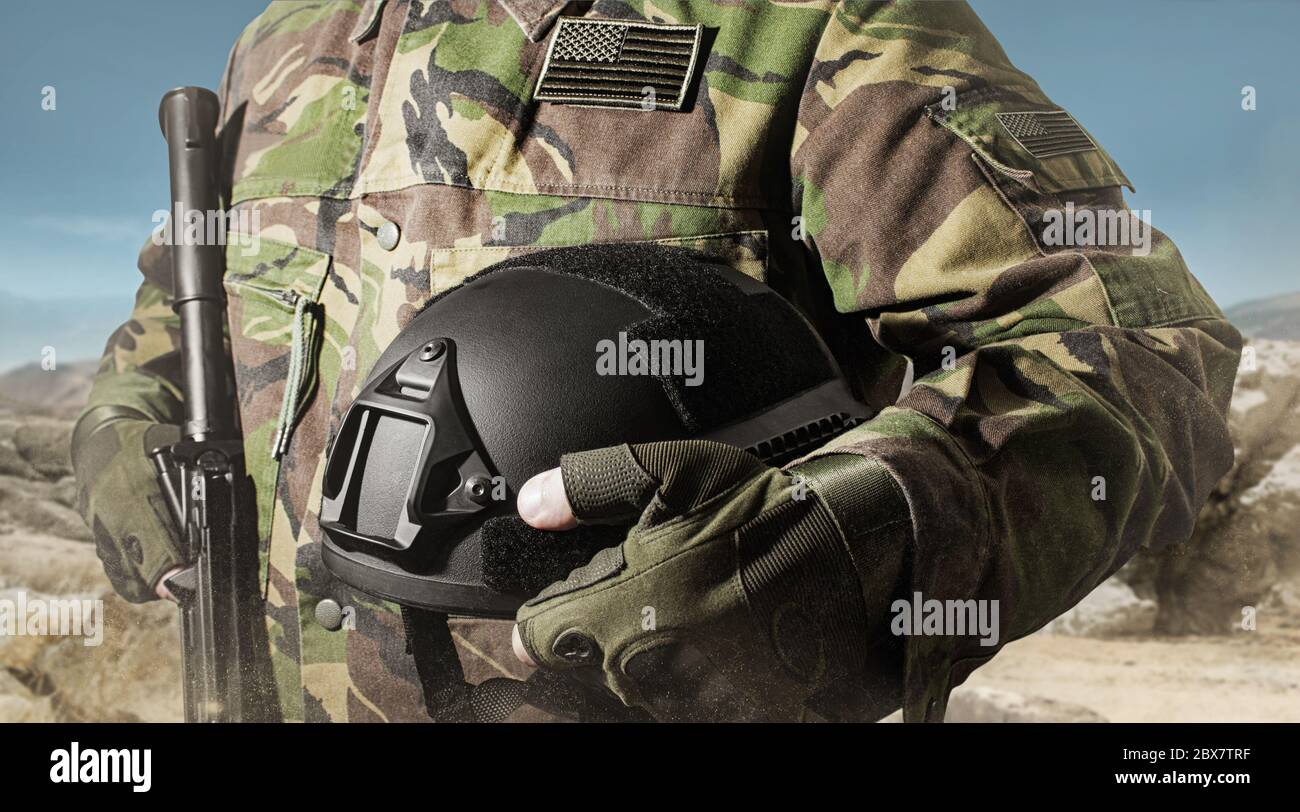 Photo of a soldier in military jacket holding helmet and standing on ...