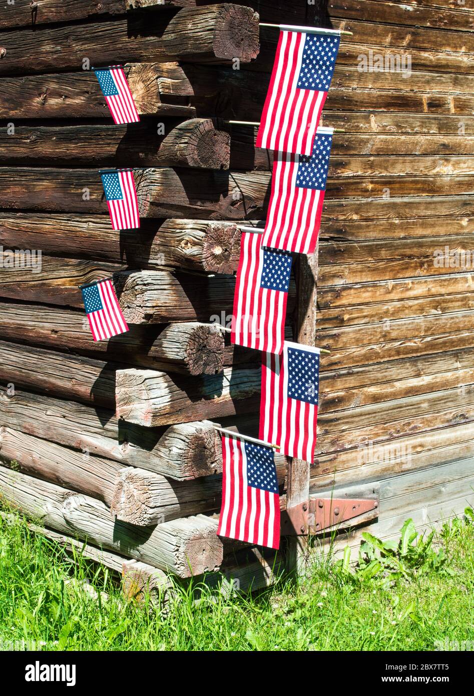 8 small American flags displayed on the exterior corner of a rustic log ...