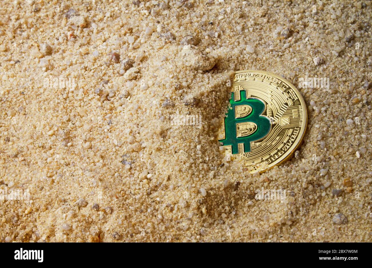 Photo of a golden bitcoin coin buried in sand Stock Photo - Alamy