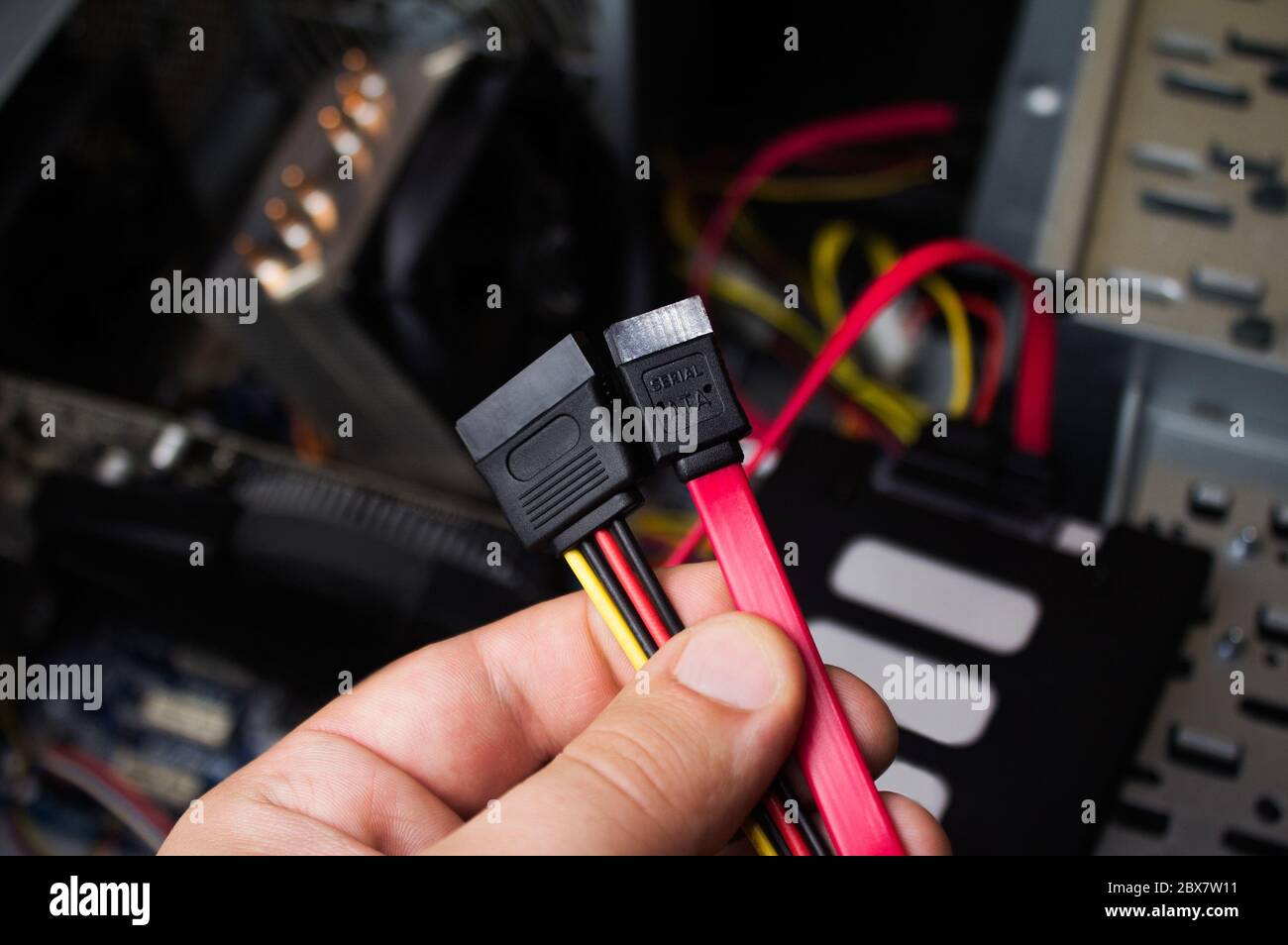 First person view of a hand holding SSD cables on motherboard ...