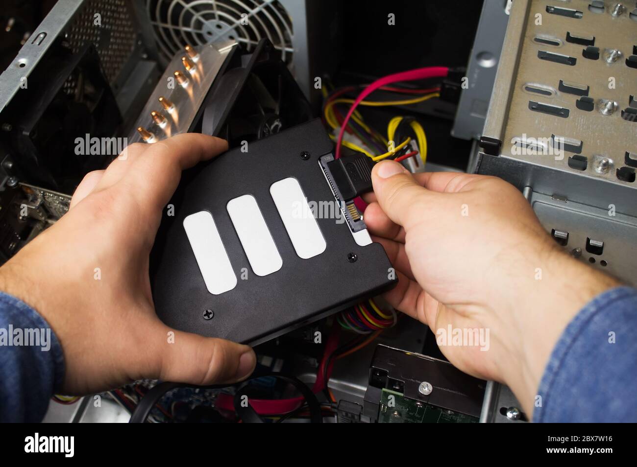 First person view hands holding & connecting SSD drive to a motherboard ...