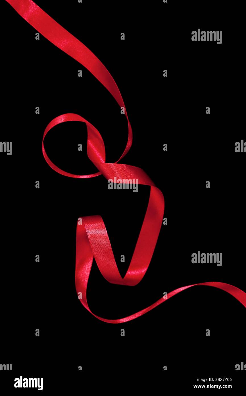 Red satin ribbon curling over black background Stock Photo - Alamy