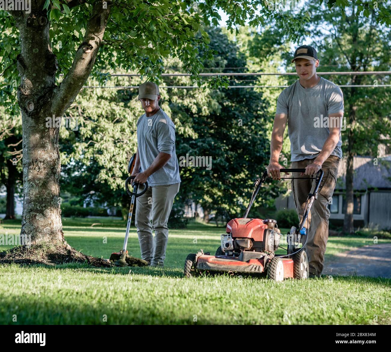 two men weed eating and mowing yard for landscaping job in Kentucky ...