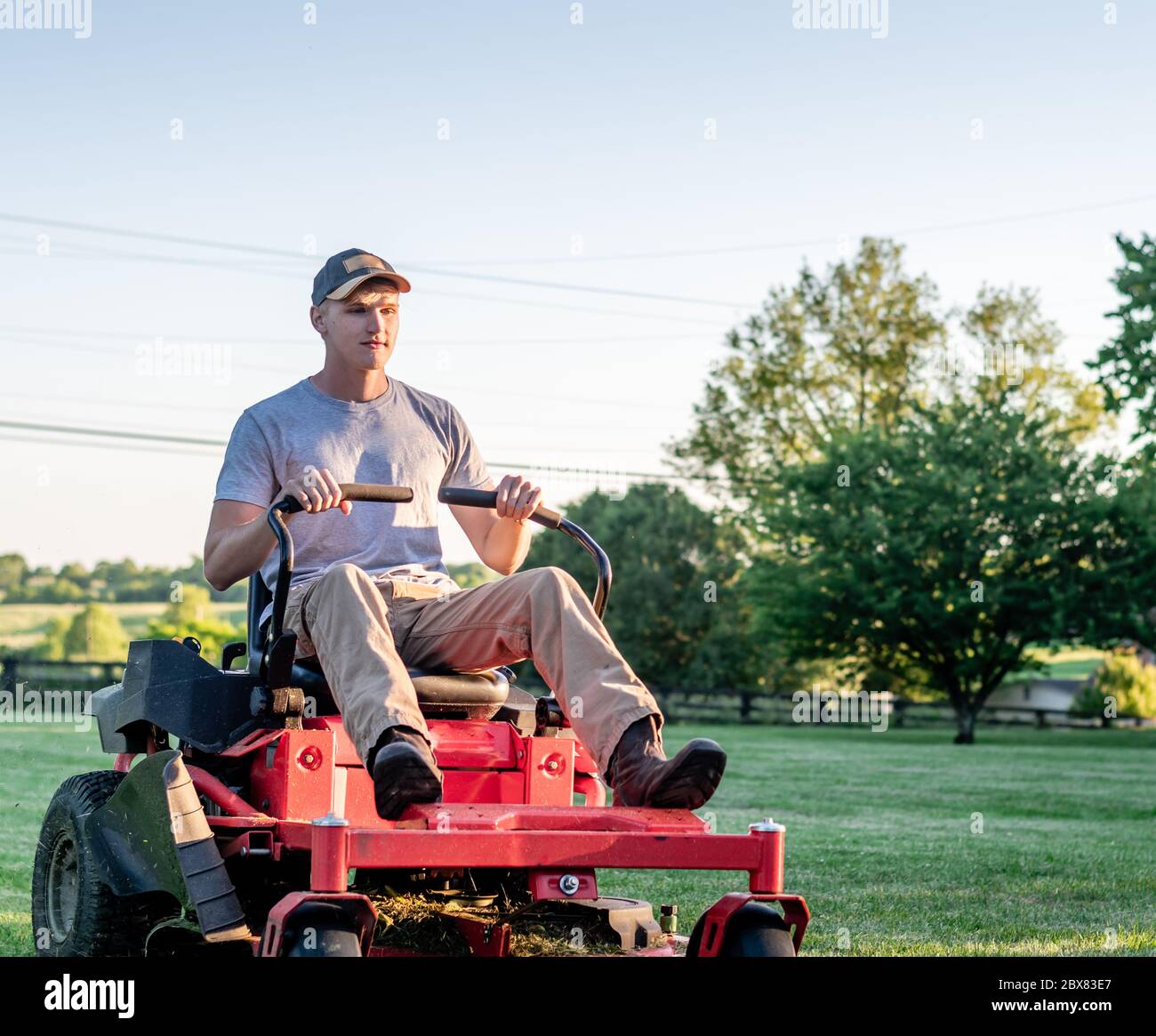 Young caucasian man working as landscaper on riding mower/ zero turn ...