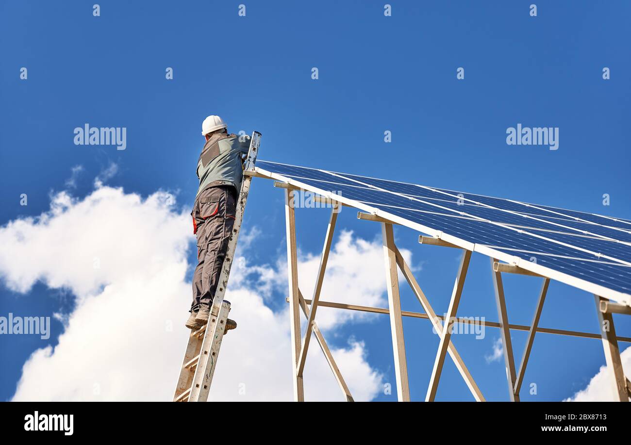 Side view of male worker installing solar panels and support structures ...