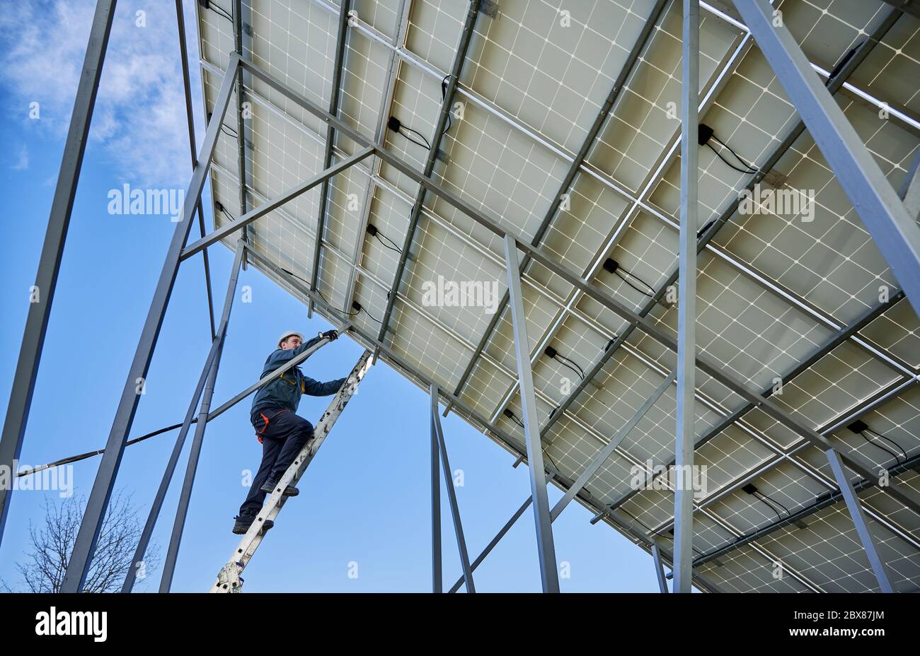 Full length of electrician standing on ladder and installing ...