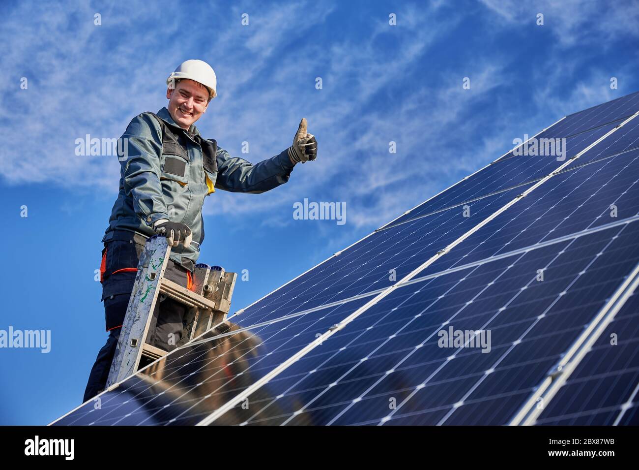 Portrait of a smiling worker, installing solar batteries, standing on ...